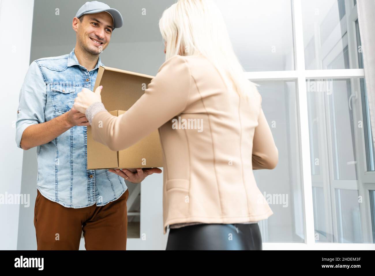 woman receiving package from delivery man Stock Photo - Alamy