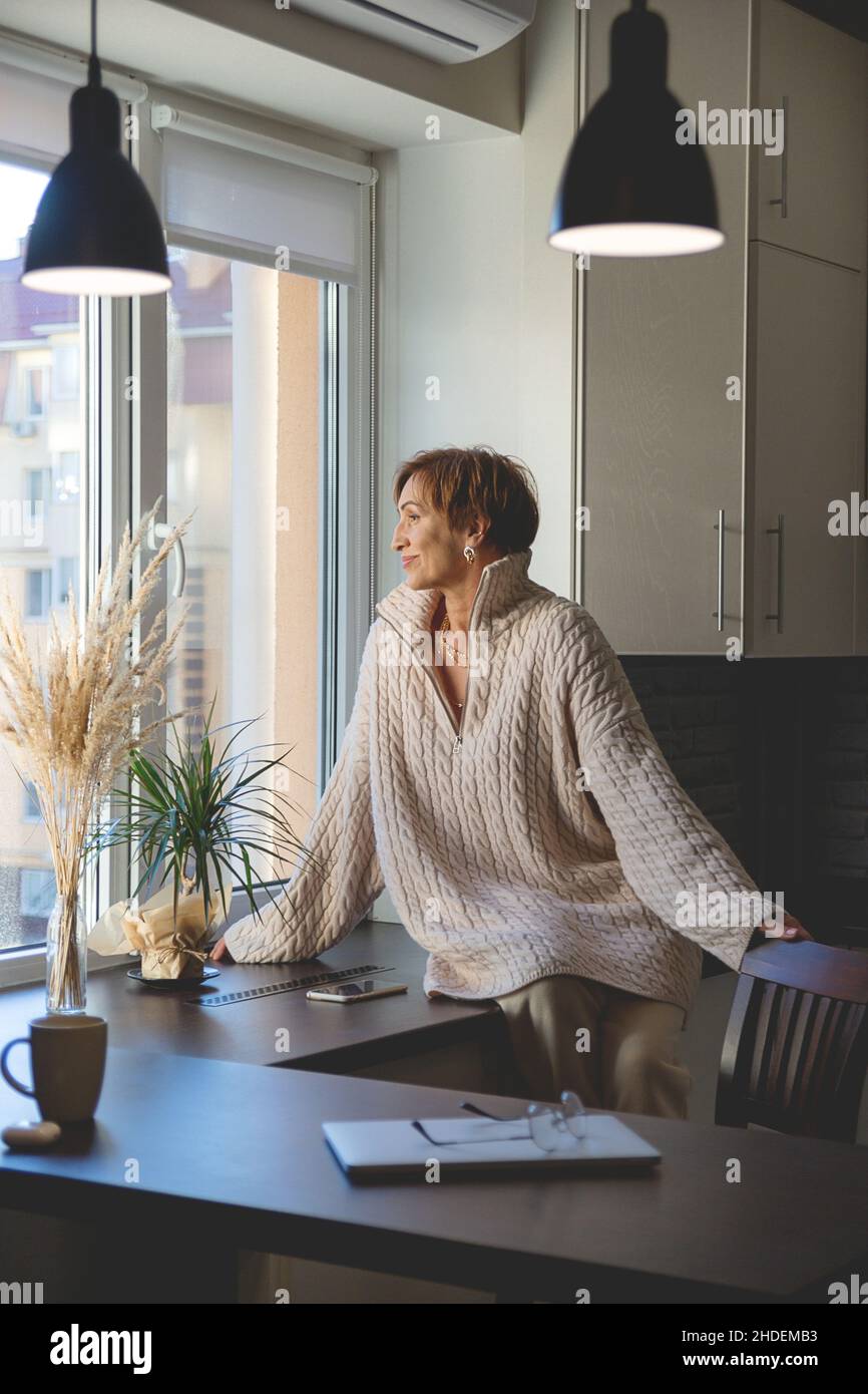 Beautiful middle-aged baby boomer woman in beige sweater sitting on ...