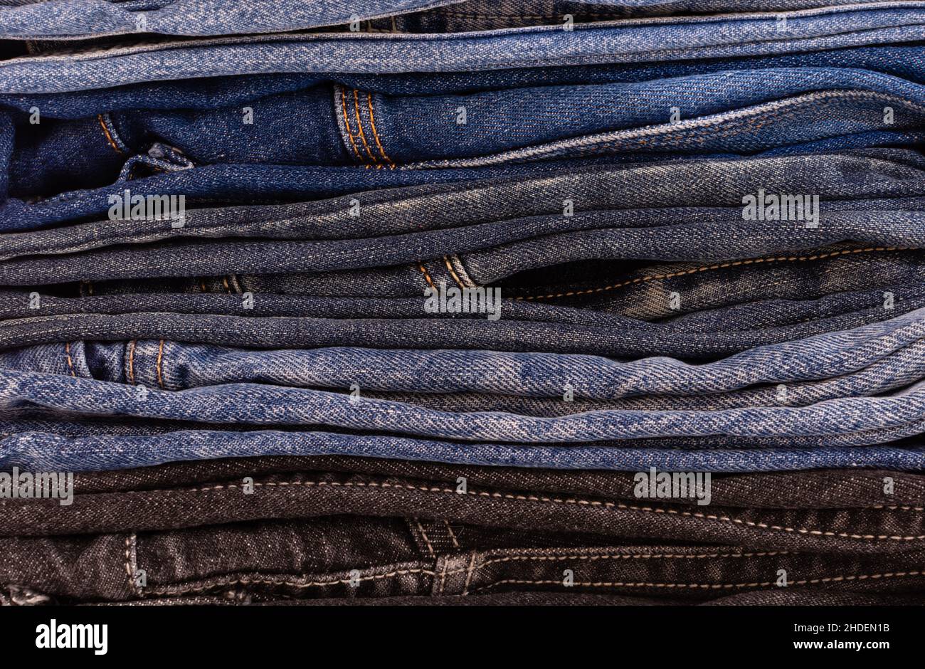 Stack of stock denim trousers of various models and colors close-up ...