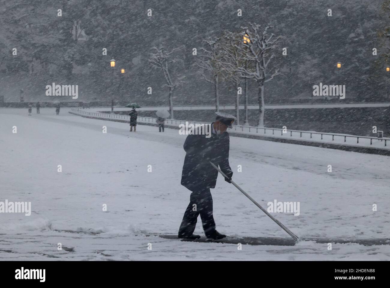 Tokyo, Japan. 6th Jan, 2022. A police officer removes snow from a road ...