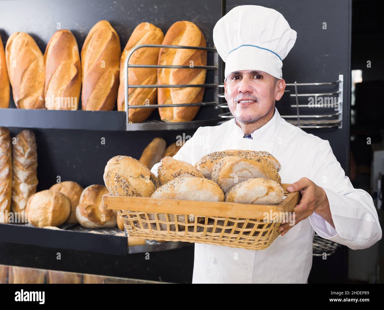 Male employee offering fresh baguettes and buns in bakery Stock Photo ...