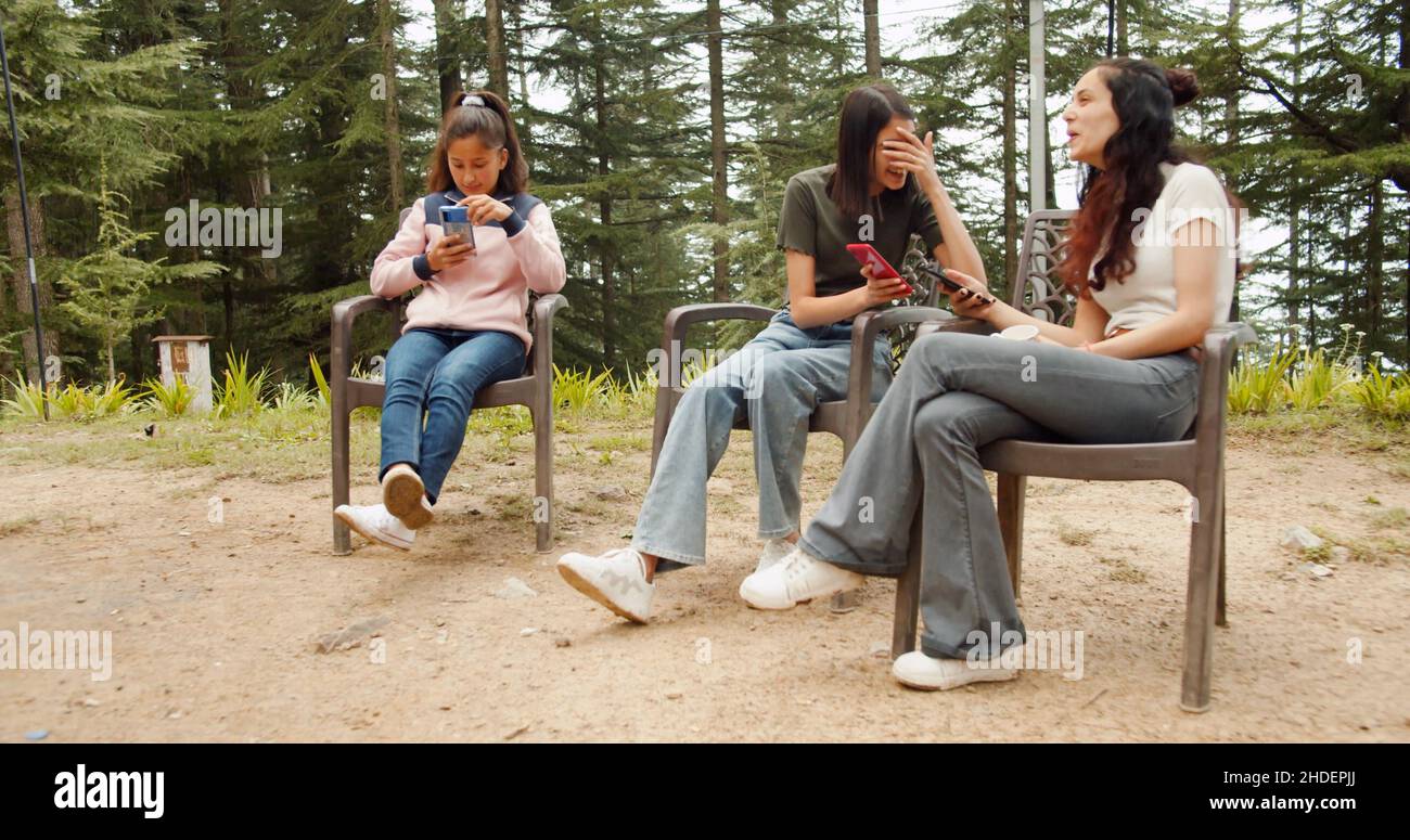 Girls sitting on the chairs outdoors Stock Photo - Alamy