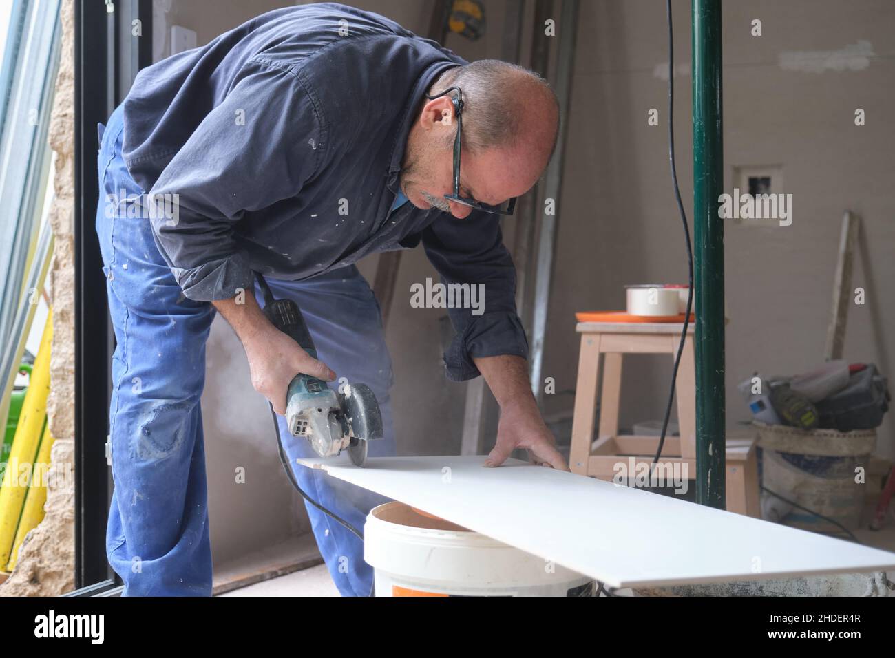 Professional tiler cutting a white ceramic tile with a radial saw Stock ...