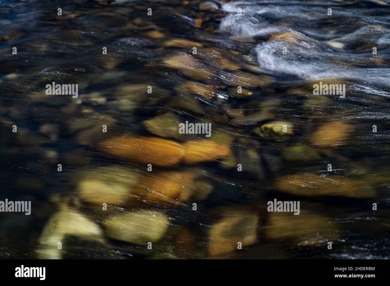 Closeup of transparent clear water flowing on the rocks of a river ...