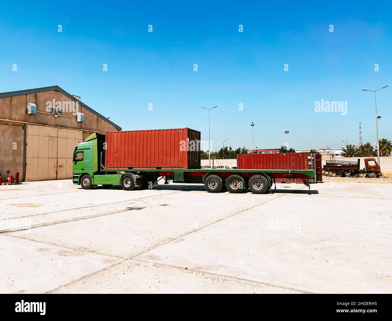 A green truck carrying a small red container Stock Photo - Alamy