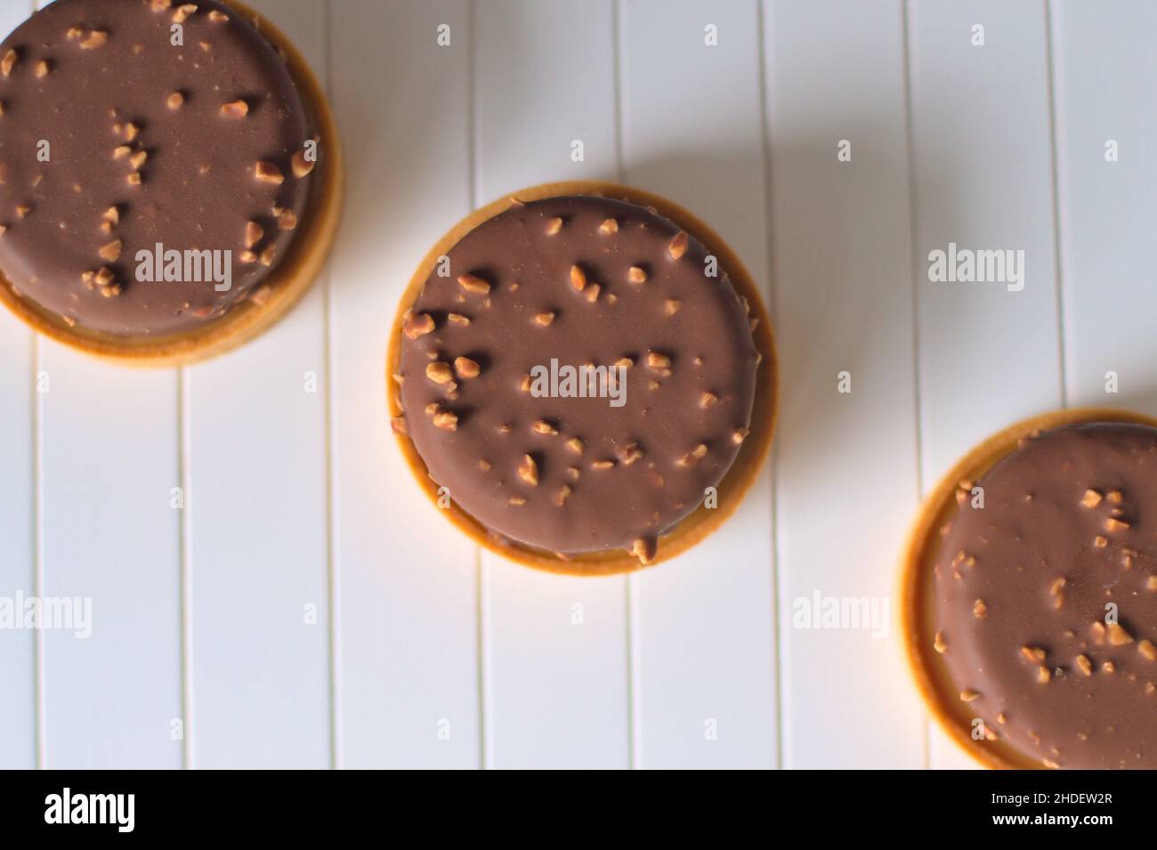 Round sweet delicious tarts covered with milk chocolate with nut pieces ...