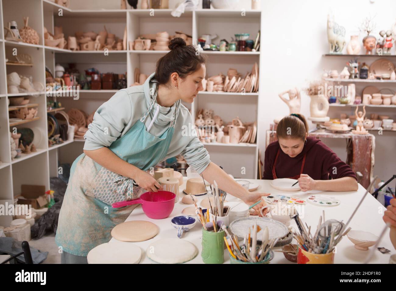 Female ceramists working at their studio, decorating plates and ...