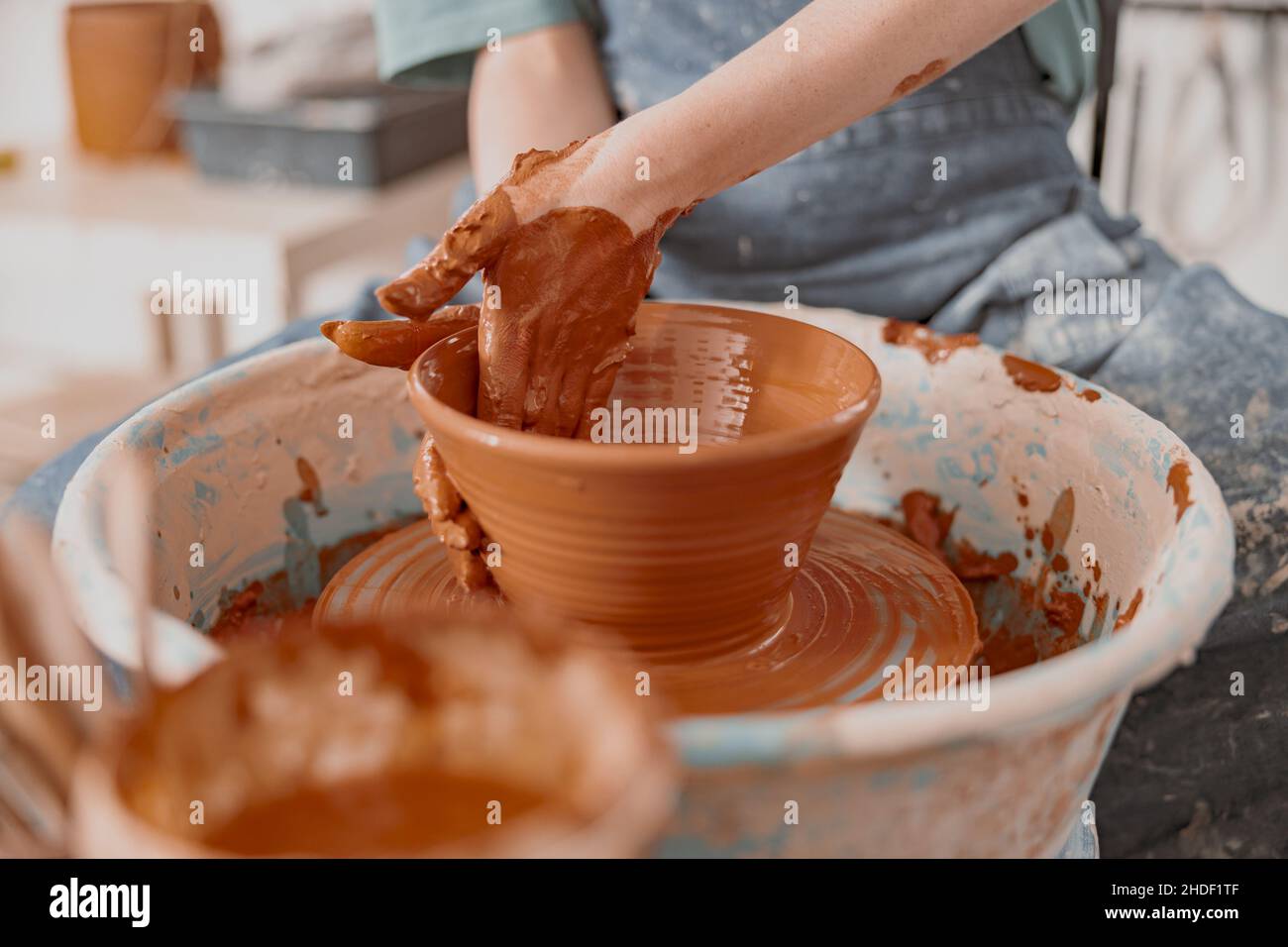 Skillful female potter creating earthen bowl on circle in workroom ...