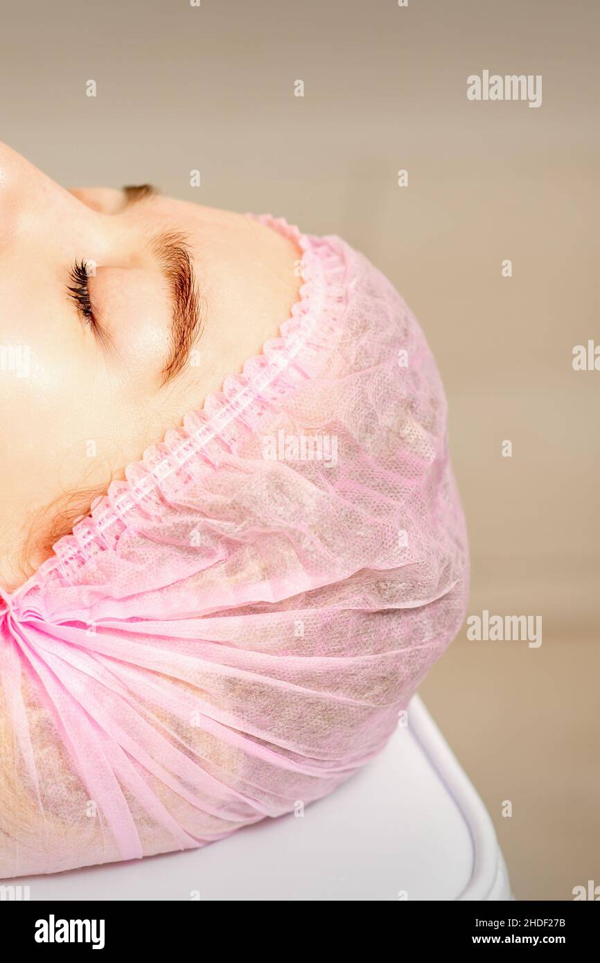 Side view of a young caucasian woman in a medical cap lying with closed ...