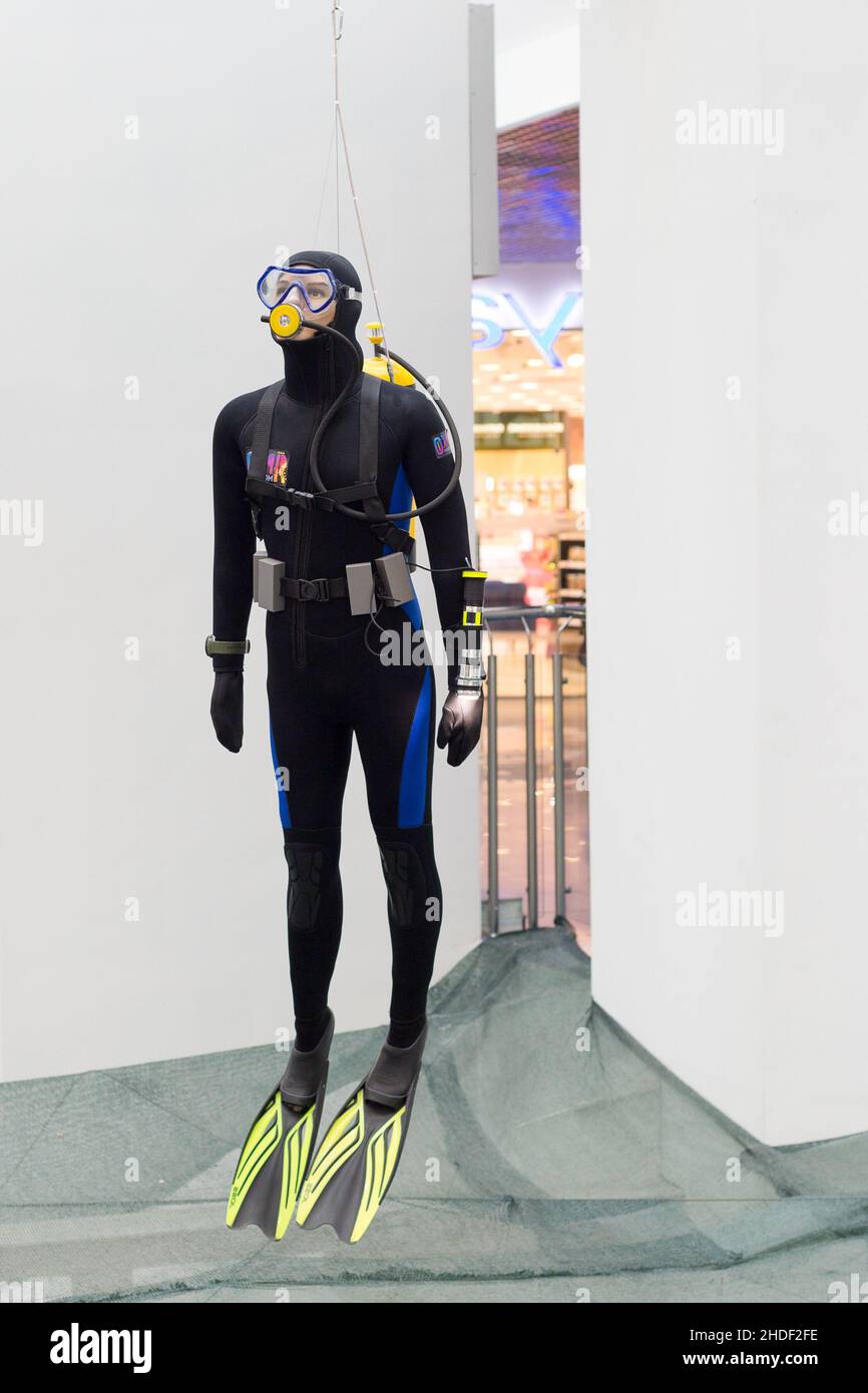A mannequin in a diving suit and yellow fins hangs over the roof of the ...