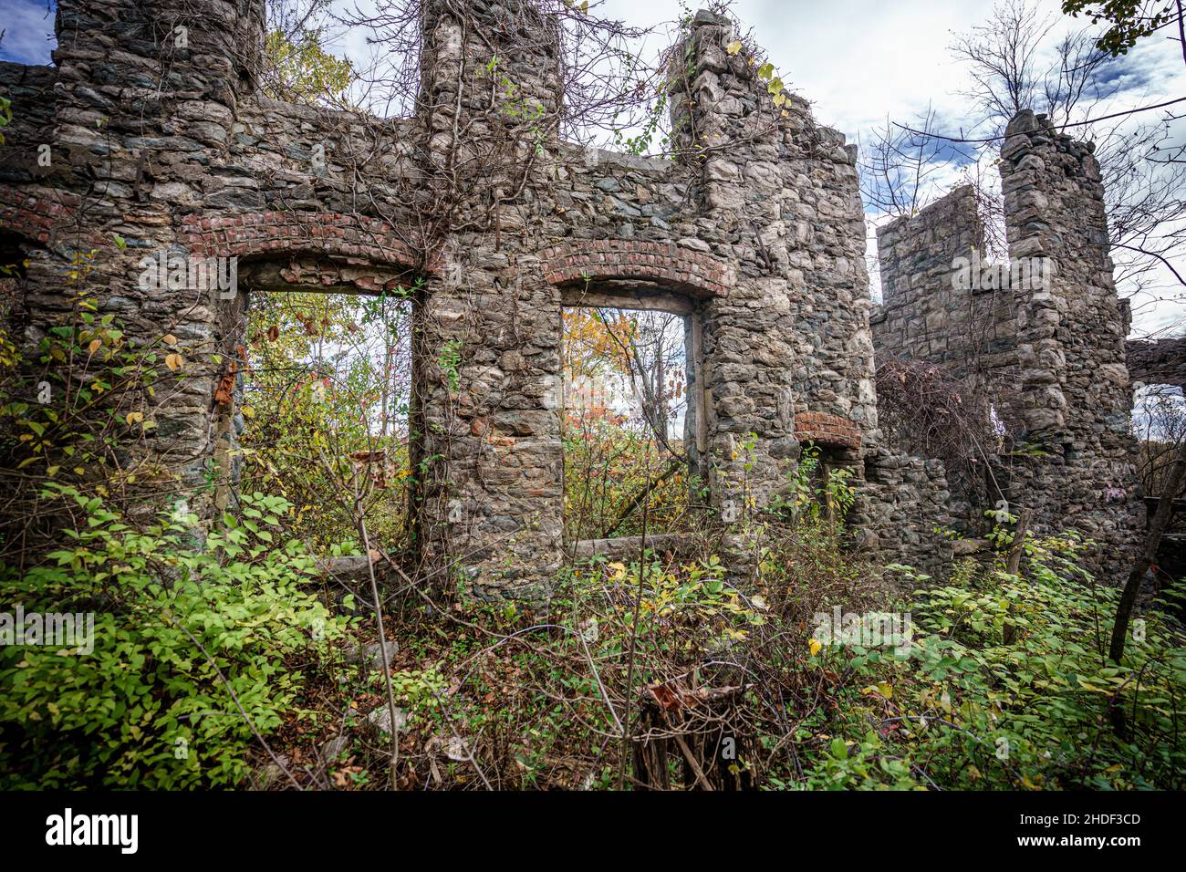Abandoned old ruin stone building with greenery under a cloudy sky ...
