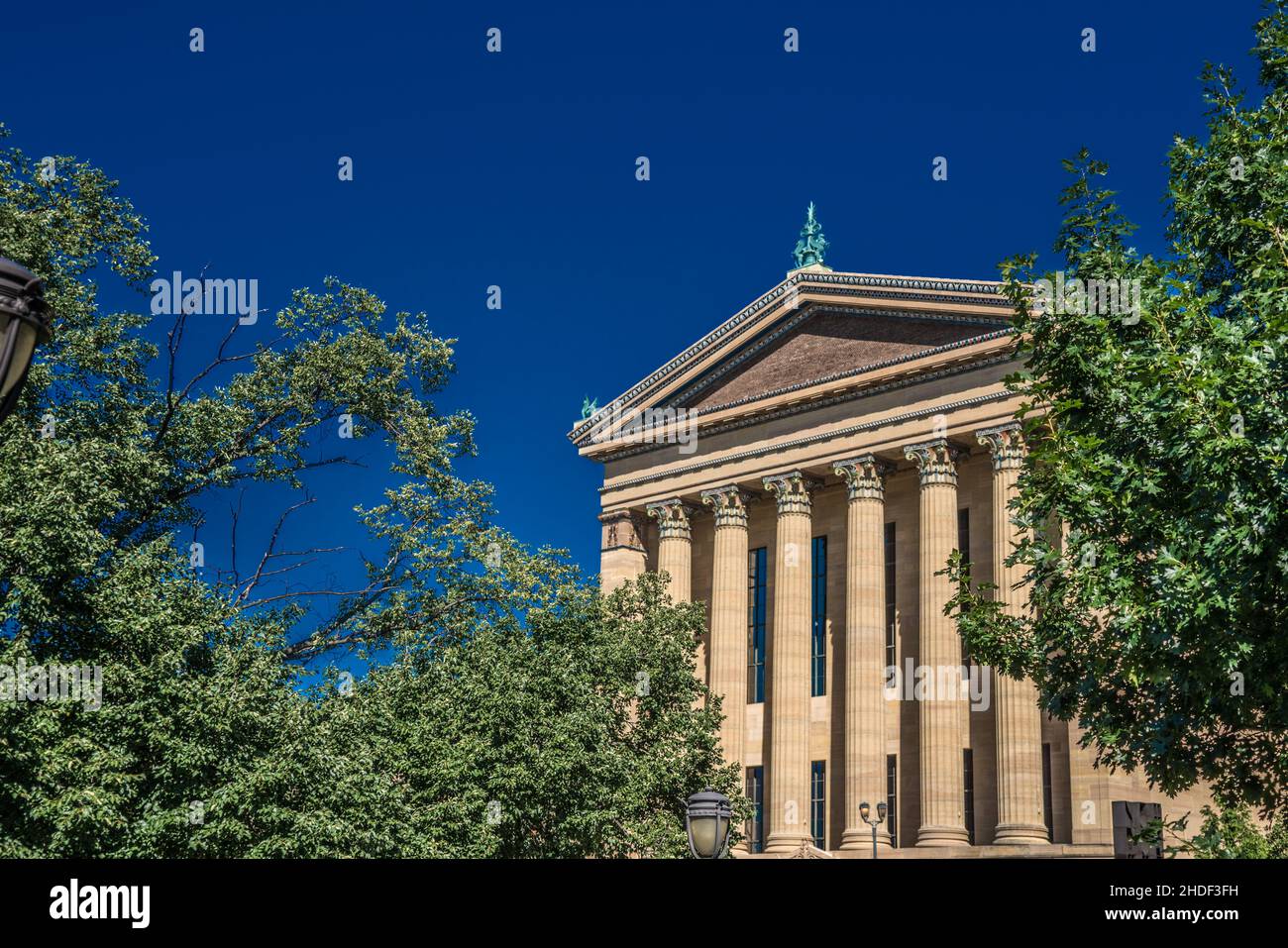 Philadelphia Museum of Art seen through greenery against a clear blue ...