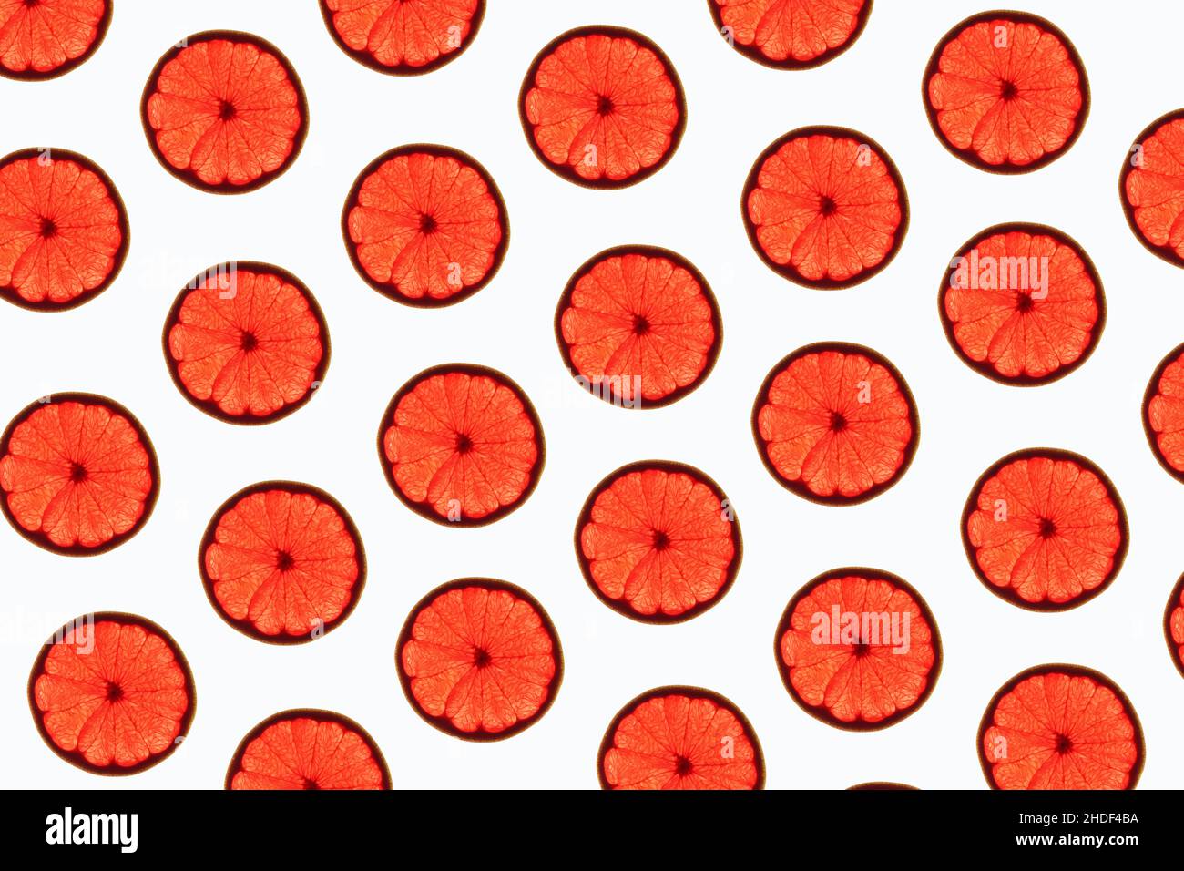 Pattern made of backlit ruby grapefruit slices on white background Stock Photo - Alamy
