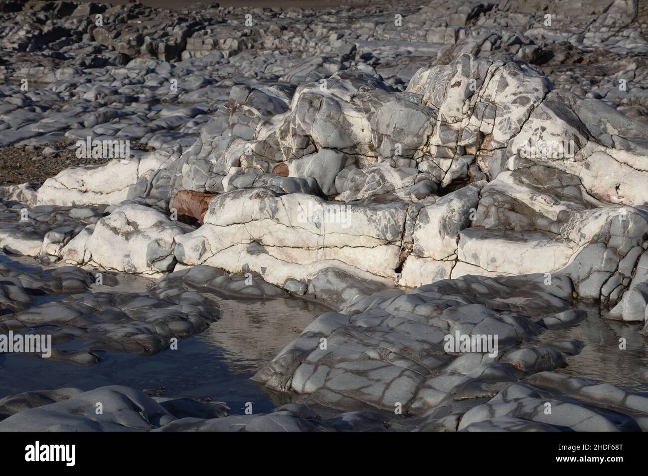 A large rock with plenty of quartz running through it on the beach and ...