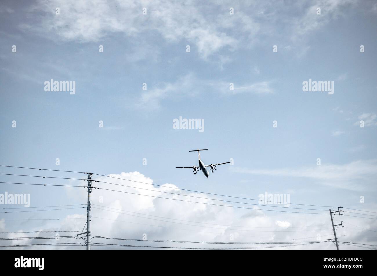 Plane flying over electrical poles Stock Photo - Alamy