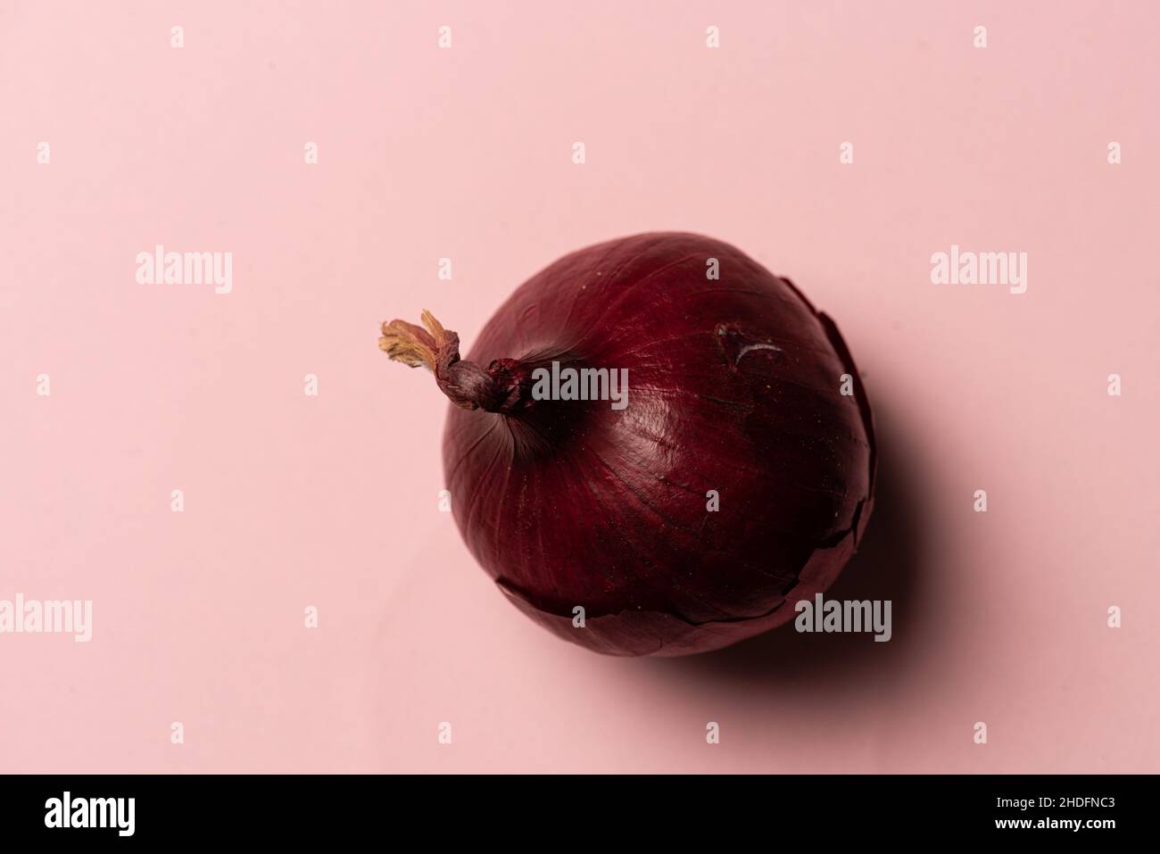 Red onion om pink background Stock Photo - Alamy