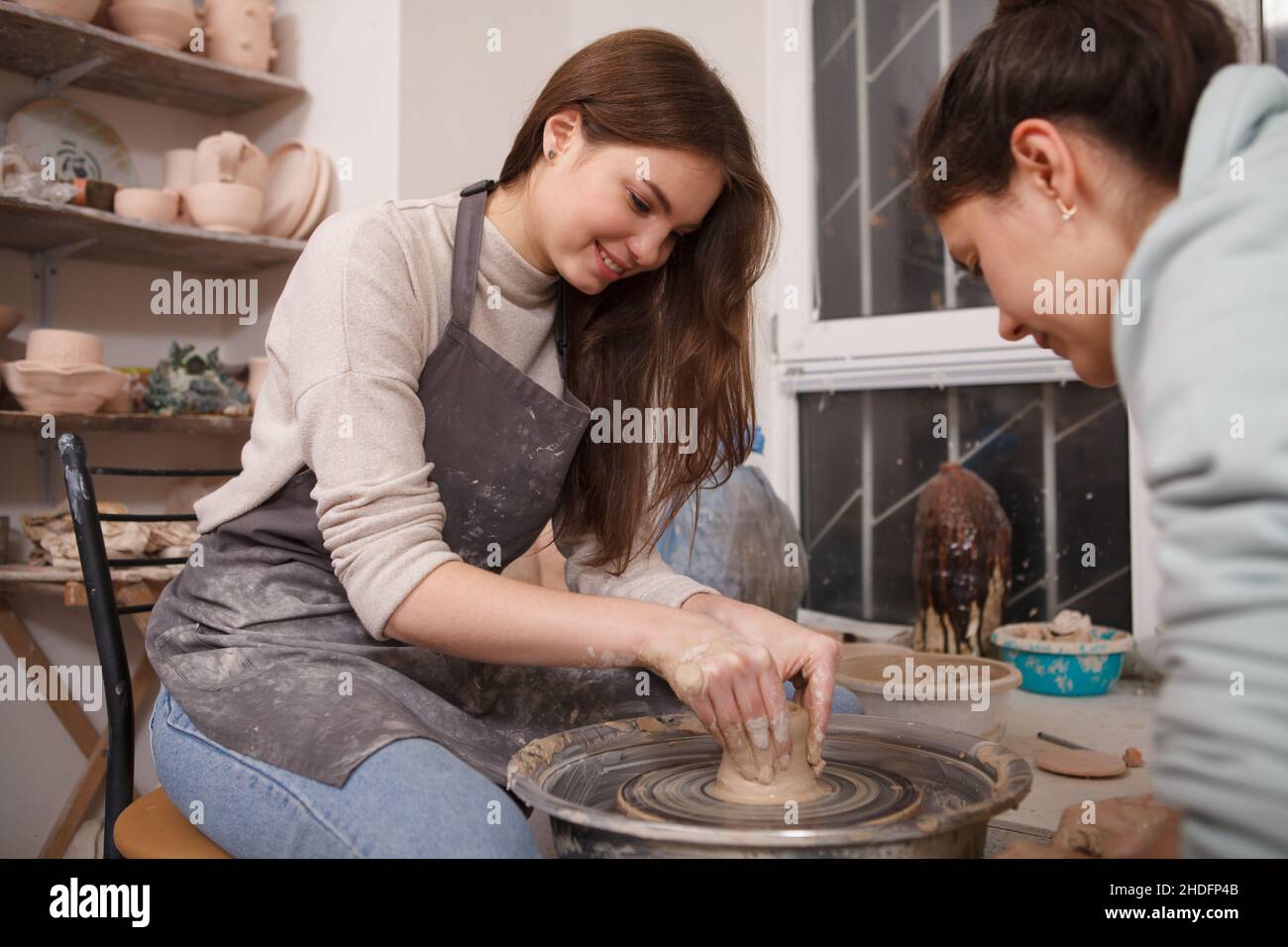 Cheerful woman enjoying learning at pottery school, professional ...
