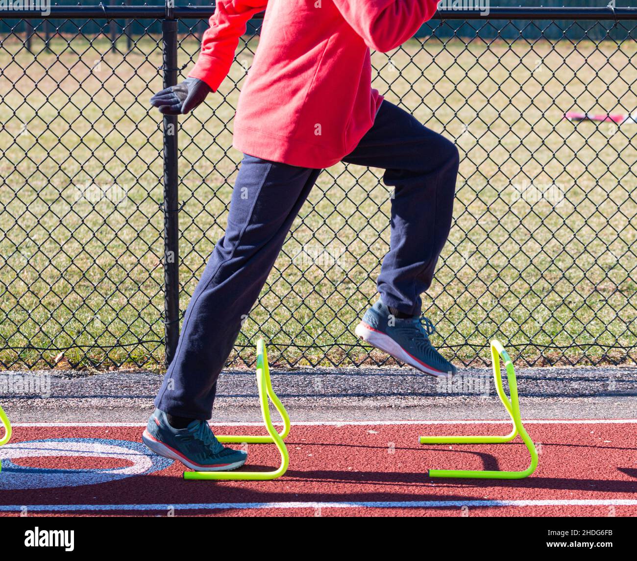 Side view of a high school boy standing over a yellow mini hurdle in ...