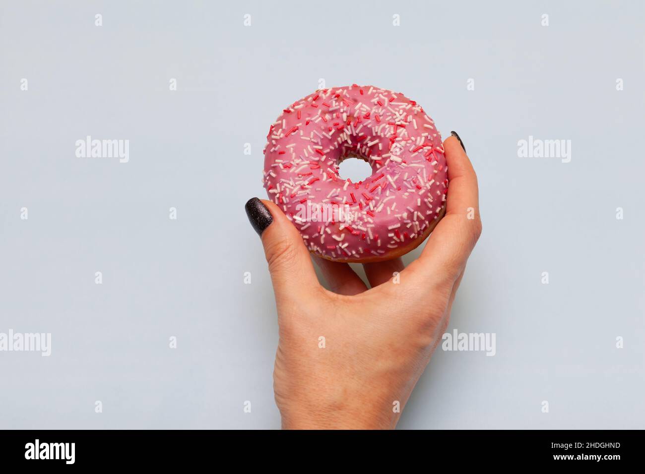 female hand holding donut on blue green background Stock Photo - Alamy