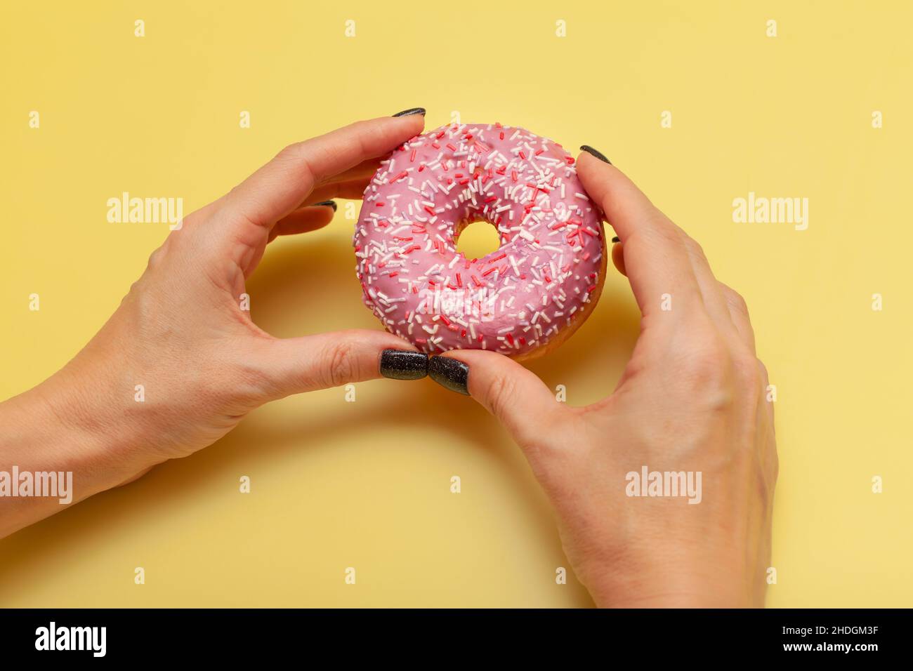 female hand holding donut on yellow green background Stock Photo - Alamy