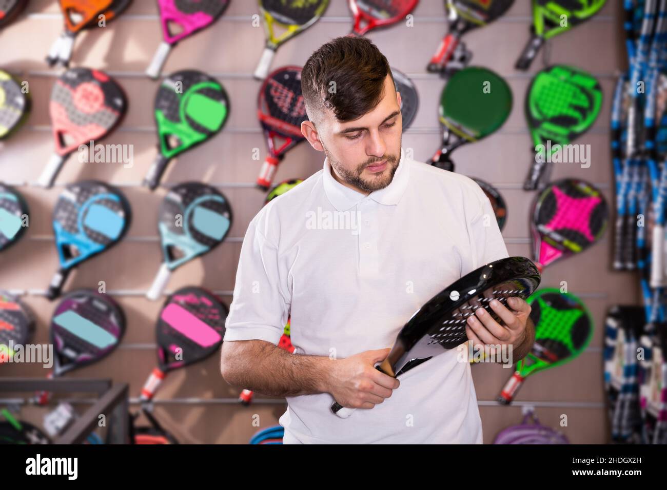 Serious young man looking for new padel racquet in store Stock Photo ...