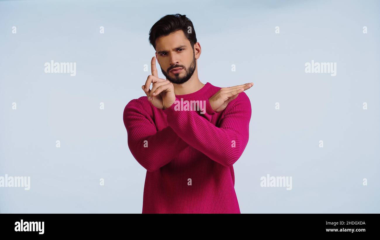 serious man in pink sweater crossing hands and pointing with finger ...