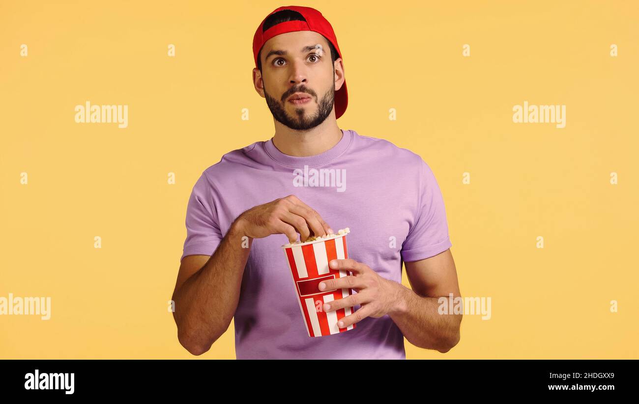 man watching movie and reaching popcorn bucket isolated on yellow Stock ...