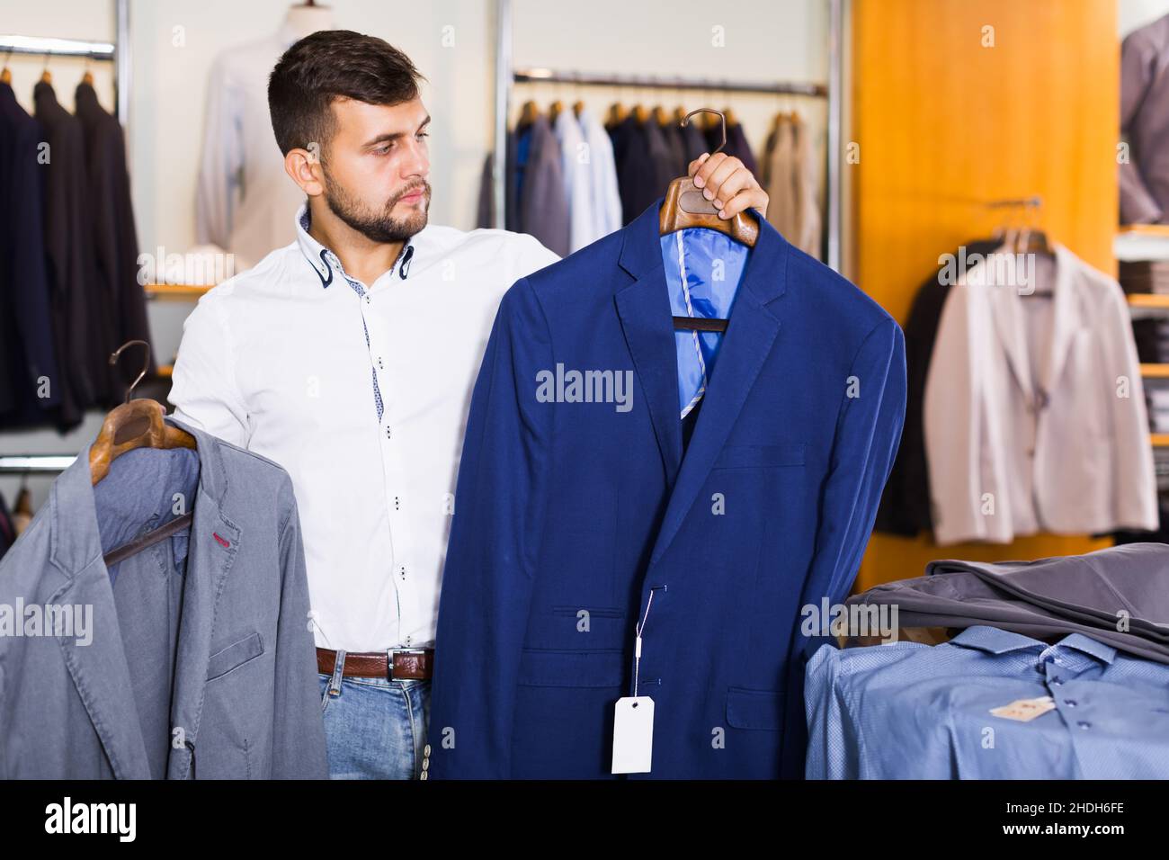 man is considering an assortment of jackets Stock Photo - Alamy