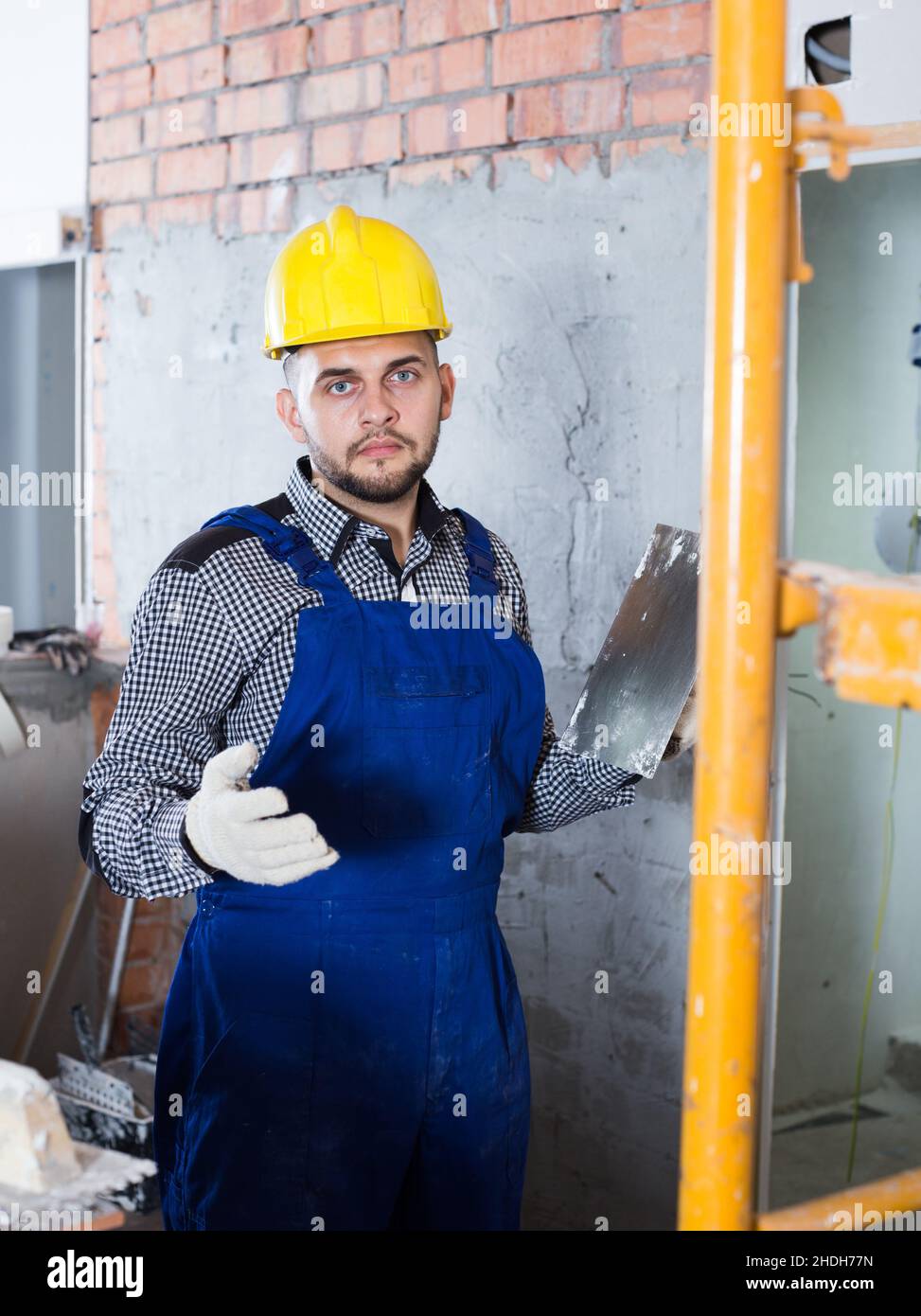 Smiling workman in the helmet ready is plastering the wall Stock Photo ...