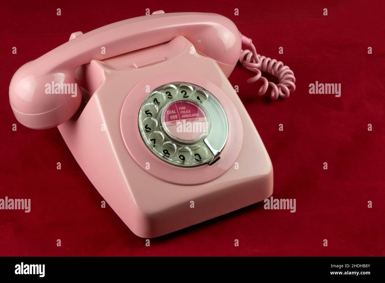 Pink vintage telephone on a mottled red table cover Stock Photo - Alamy