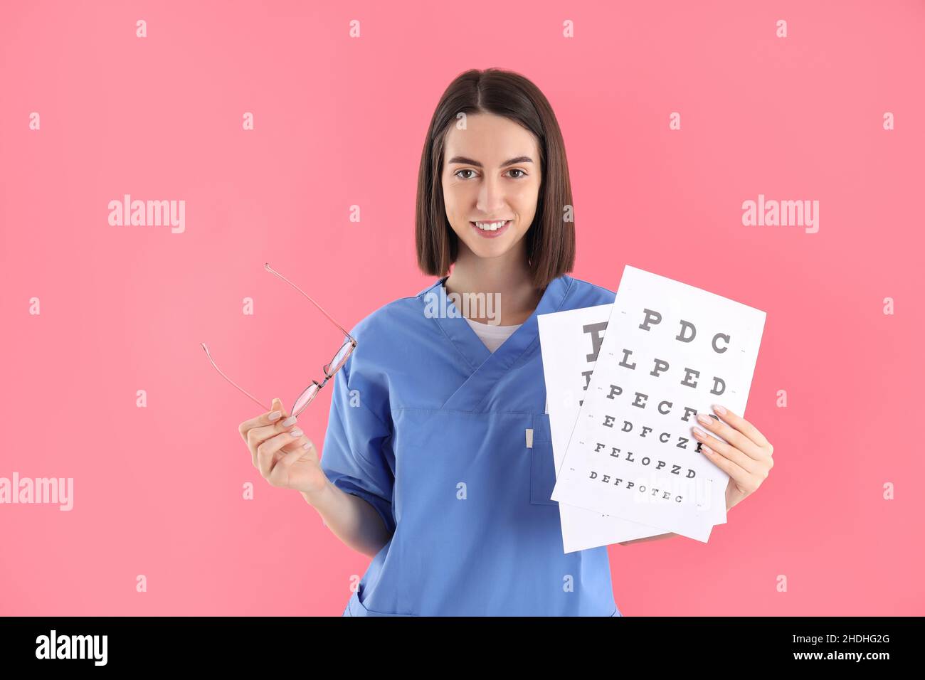 Female nurse with glasses and vision test on pink background Stock ...