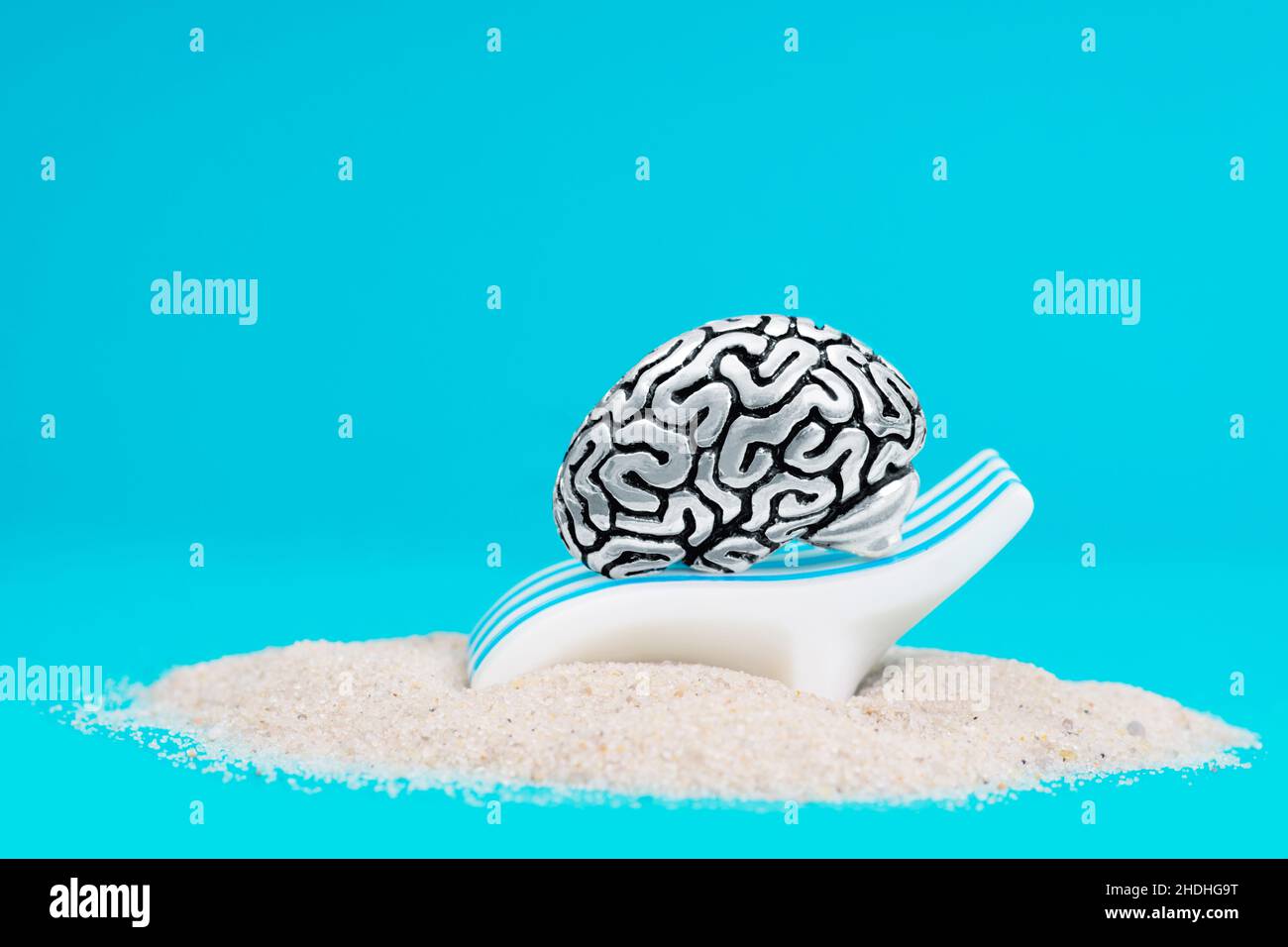 Anatomical copy of a human brain lying on a sunbed on a sandy beach ...