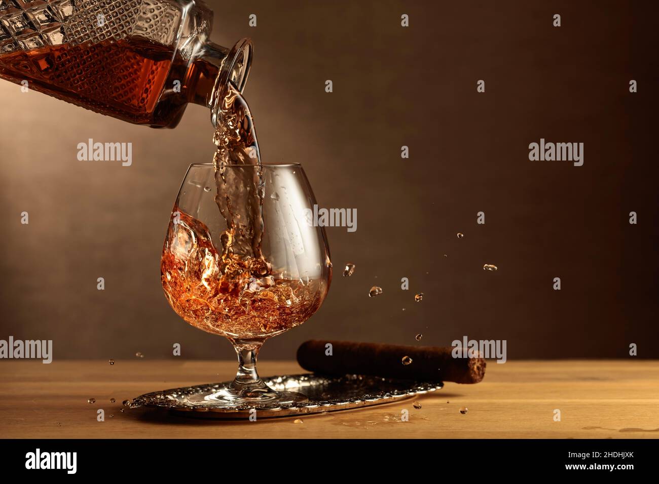 Brandy is poured from a decanter into a snifter glass. Cognac and cigar ...