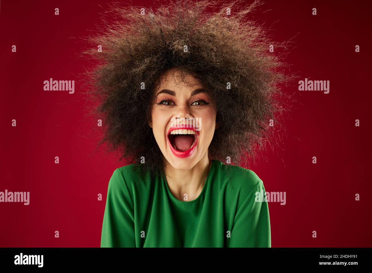 Positive young woman with curly hair grimace posing emotion studio ...