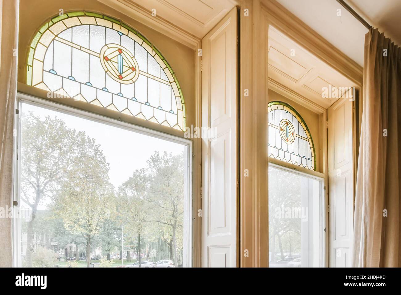 Large windows with a white frame and beige curtains and a beautiful ...