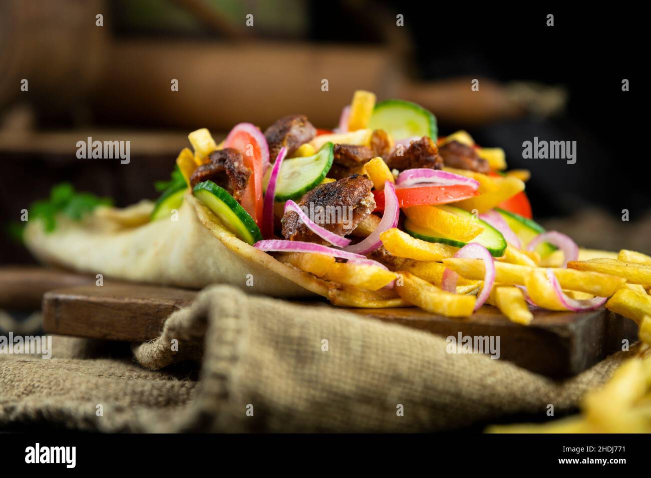 Greek gyros wrapped in pita bread on a wooden board in rustic kitchen ...