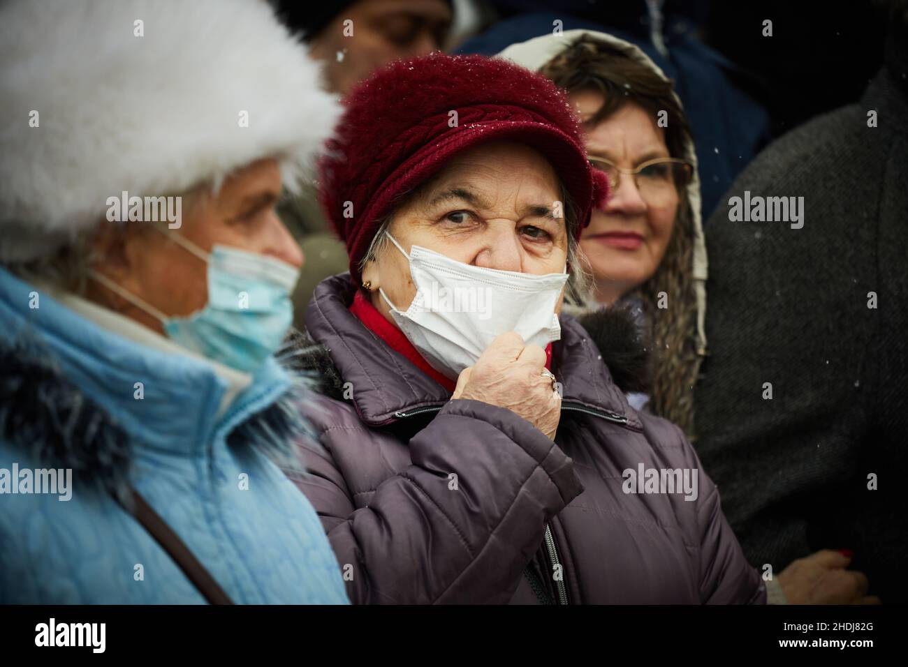 An elderly woman wearing a face mask is seen in a crowd of spectators ...