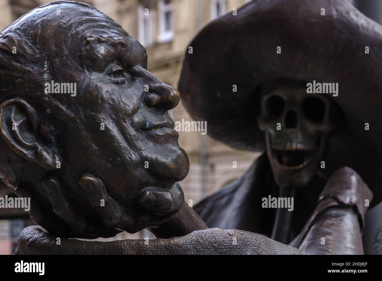 A statue of a skeleton with a hat holding the head of a man in Budapest ...