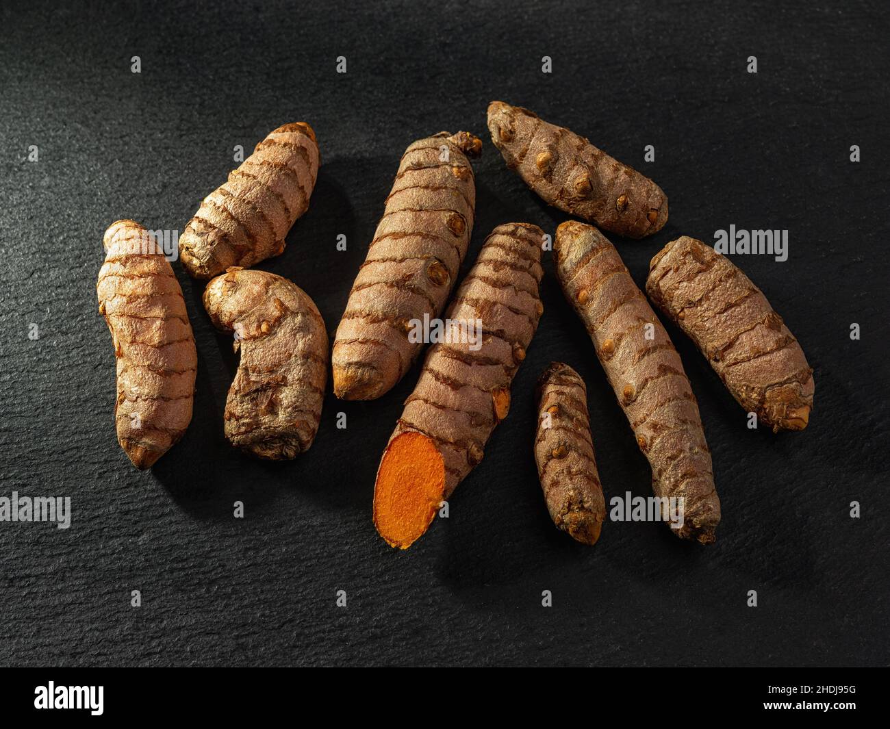 Raw organic curcuma roots on a black slate background. Fresh whole ...