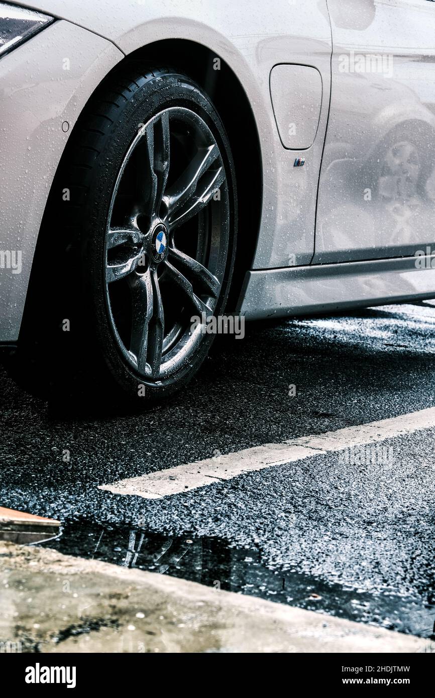 Vertical shot of a front-wheel with BMW logo on a white BMW 330e car ...