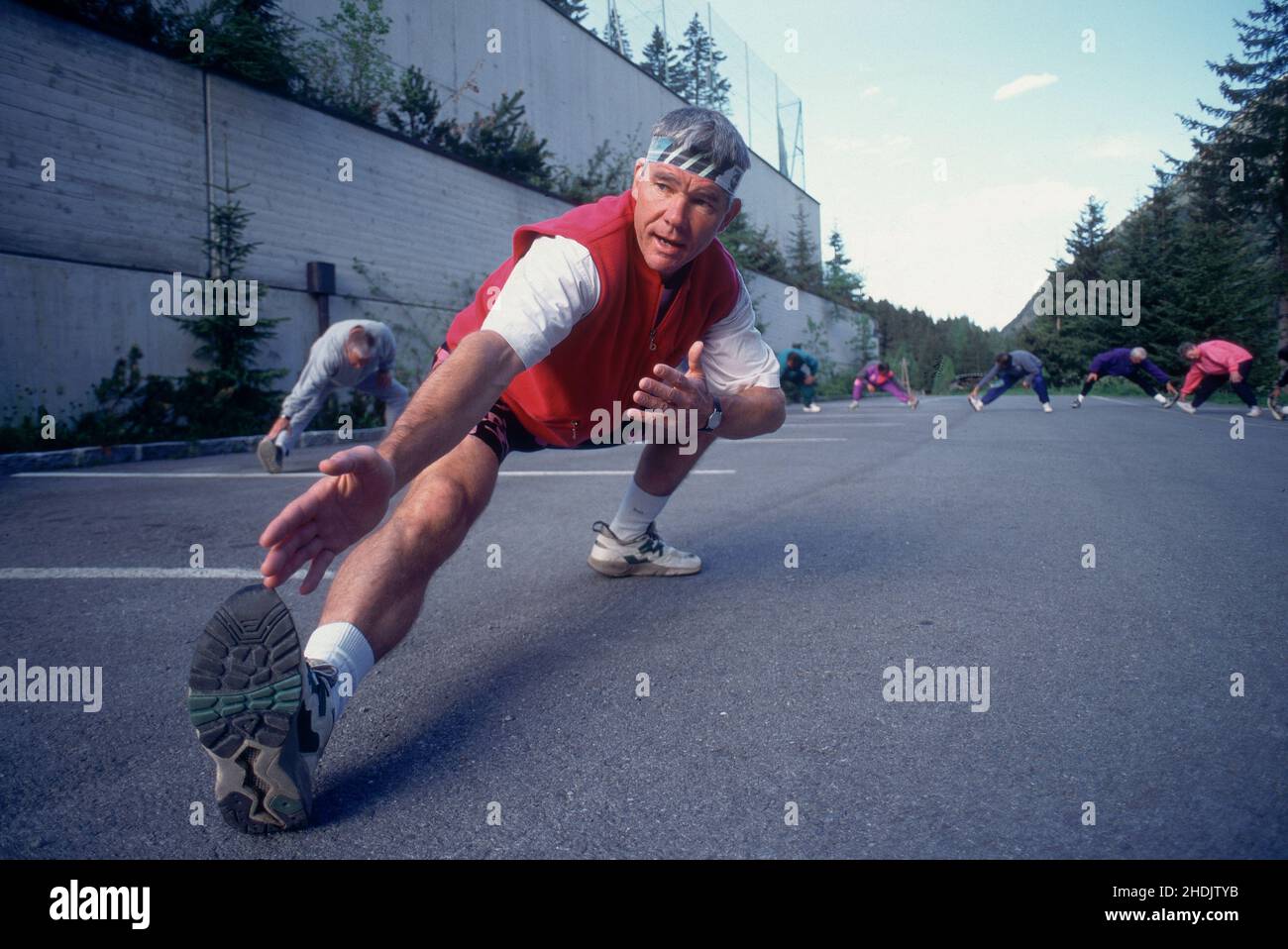 Male fitness coach doing an outdoor stretching exercise for adult ...