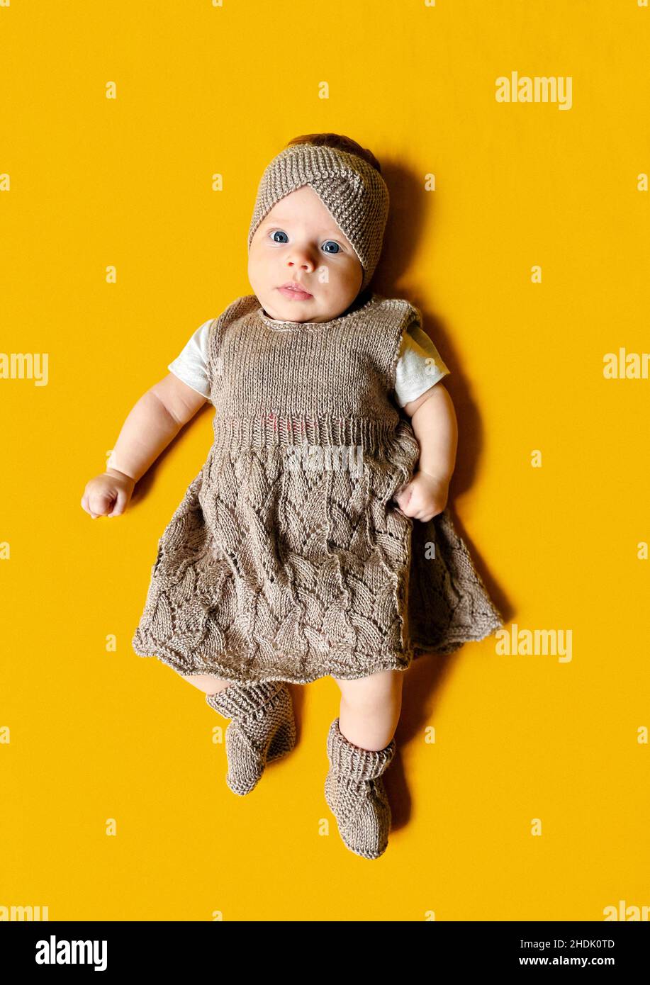 Vertical shot of a cute little Ukrainian baby girl in a brown dress ...