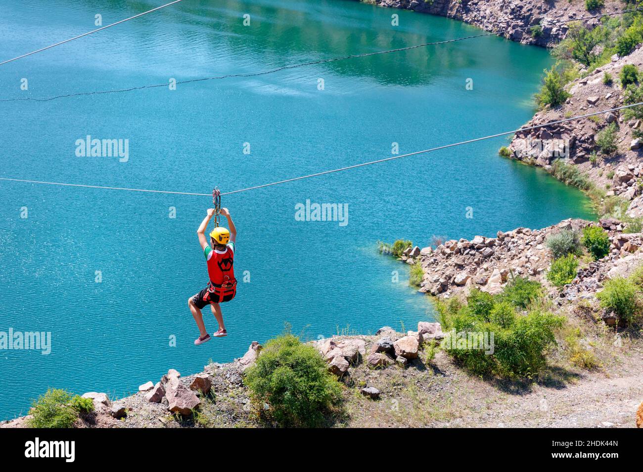 A tourist crosses a turquoise lake on a cable car against the backdrop ...