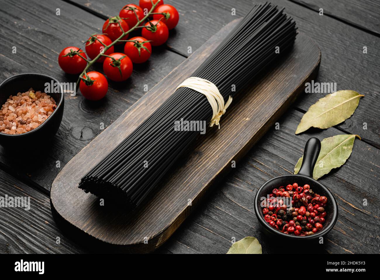 Black colored spaghetti raw dry set, on black wooden table background ...