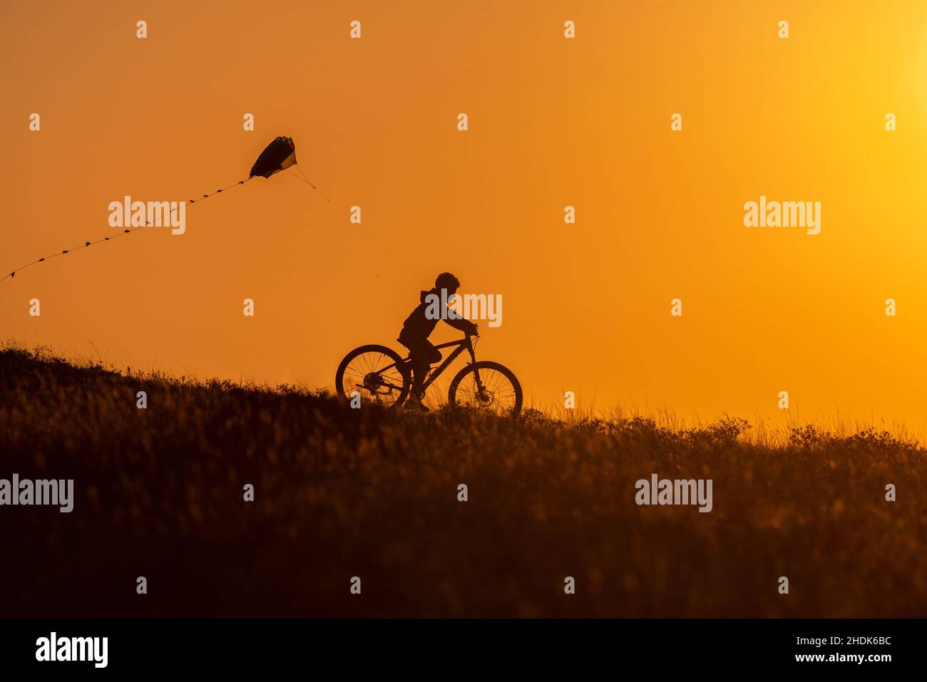 Silhouette of a child riding a bicycle with a kite in his hand Stock ...