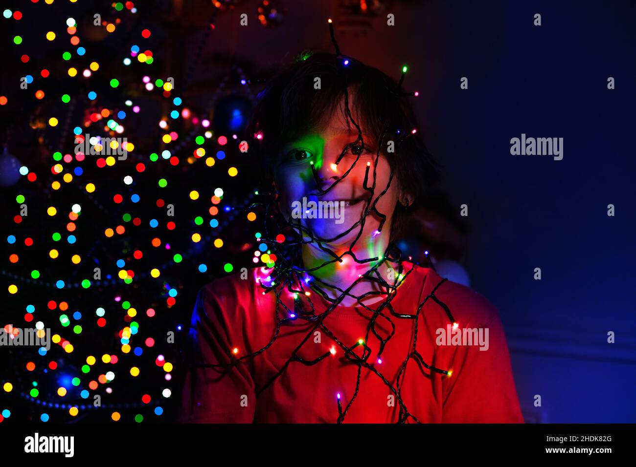 Christmas spirit: boy with garland lights on face Stock Photo - Alamy