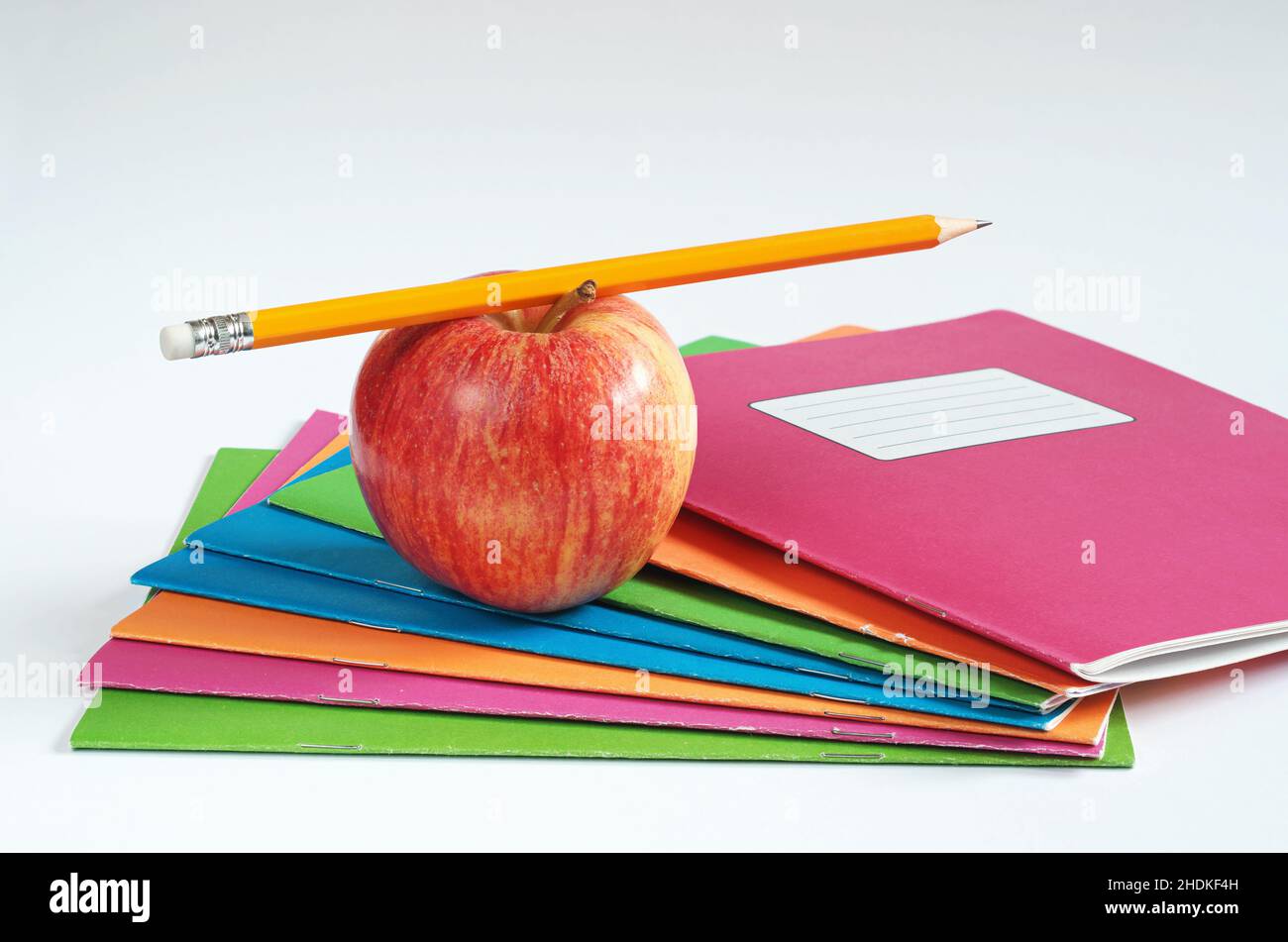 Colored school notebooks with pencil and apple on white background ...
