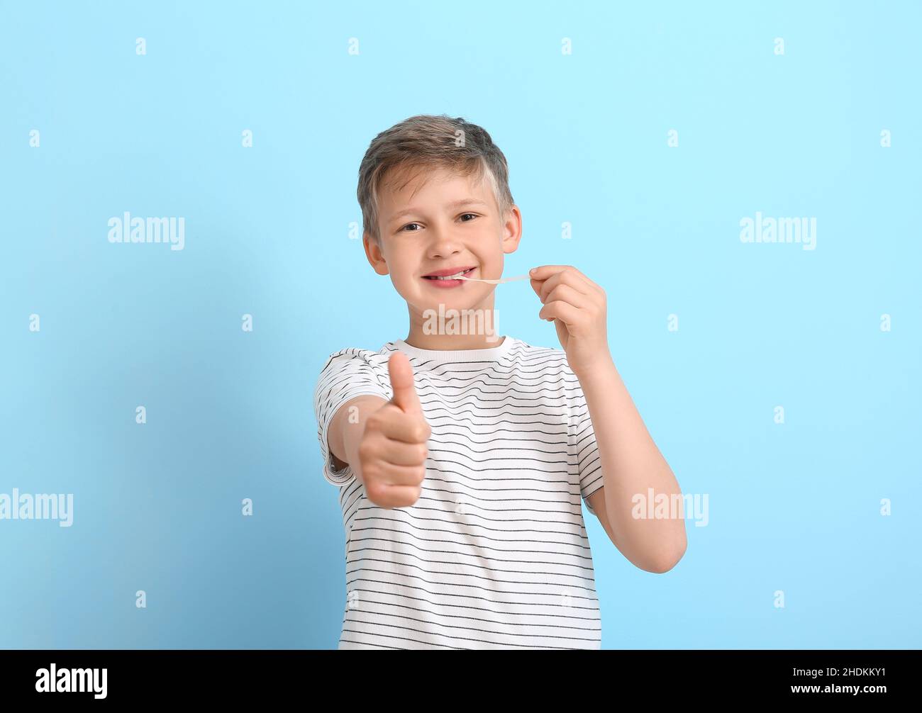Little boy with chewing gum showing thumb-up on blue background Stock ...