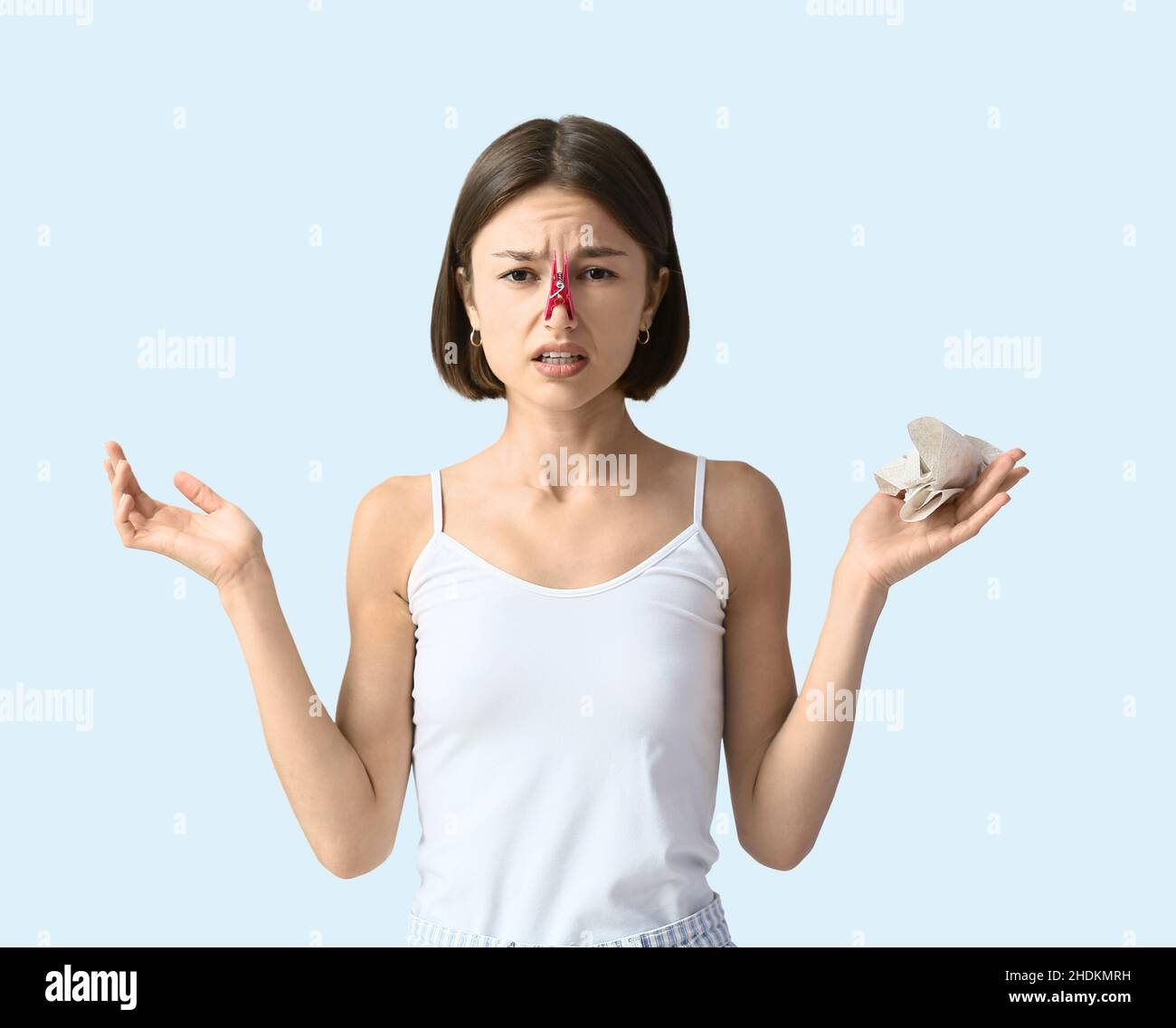 Ill young woman with clothespin on her nose against light background ...
