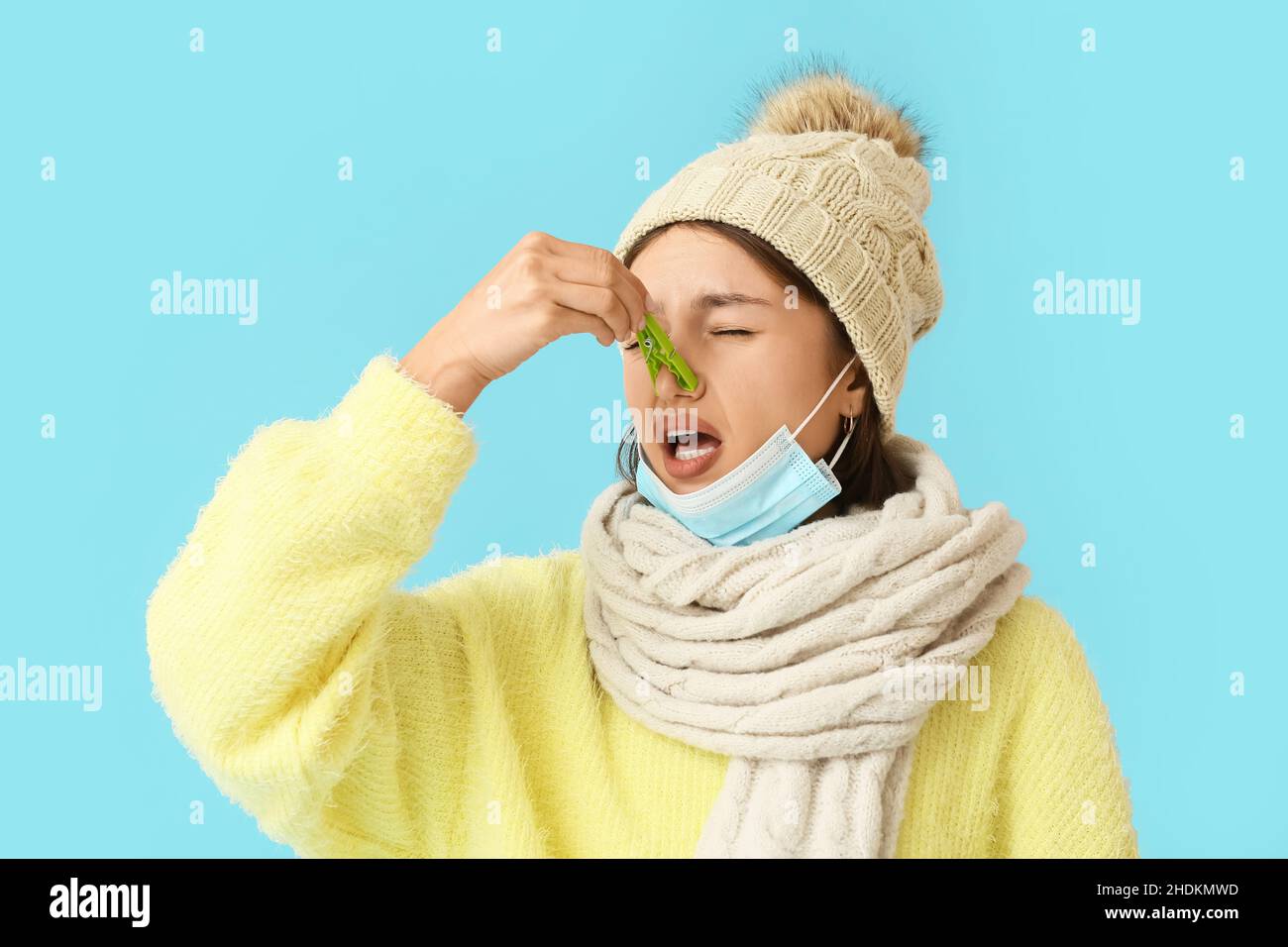 Ill young woman with clothespin on her nose against color background ...